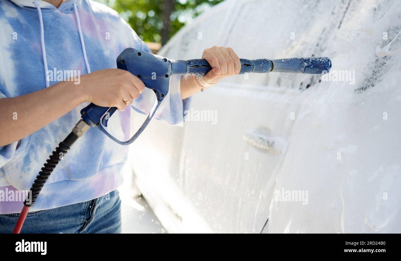 Girl washing a white car in a self-service car wash station. Wash car ...