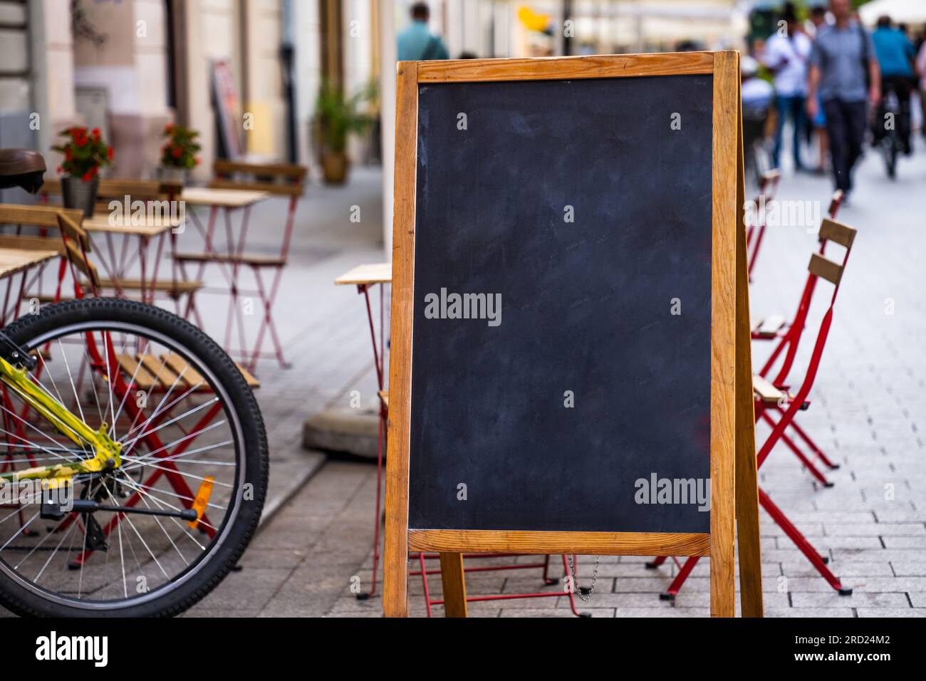 Empty easel with black board for menu offers next to cafe at street of ...