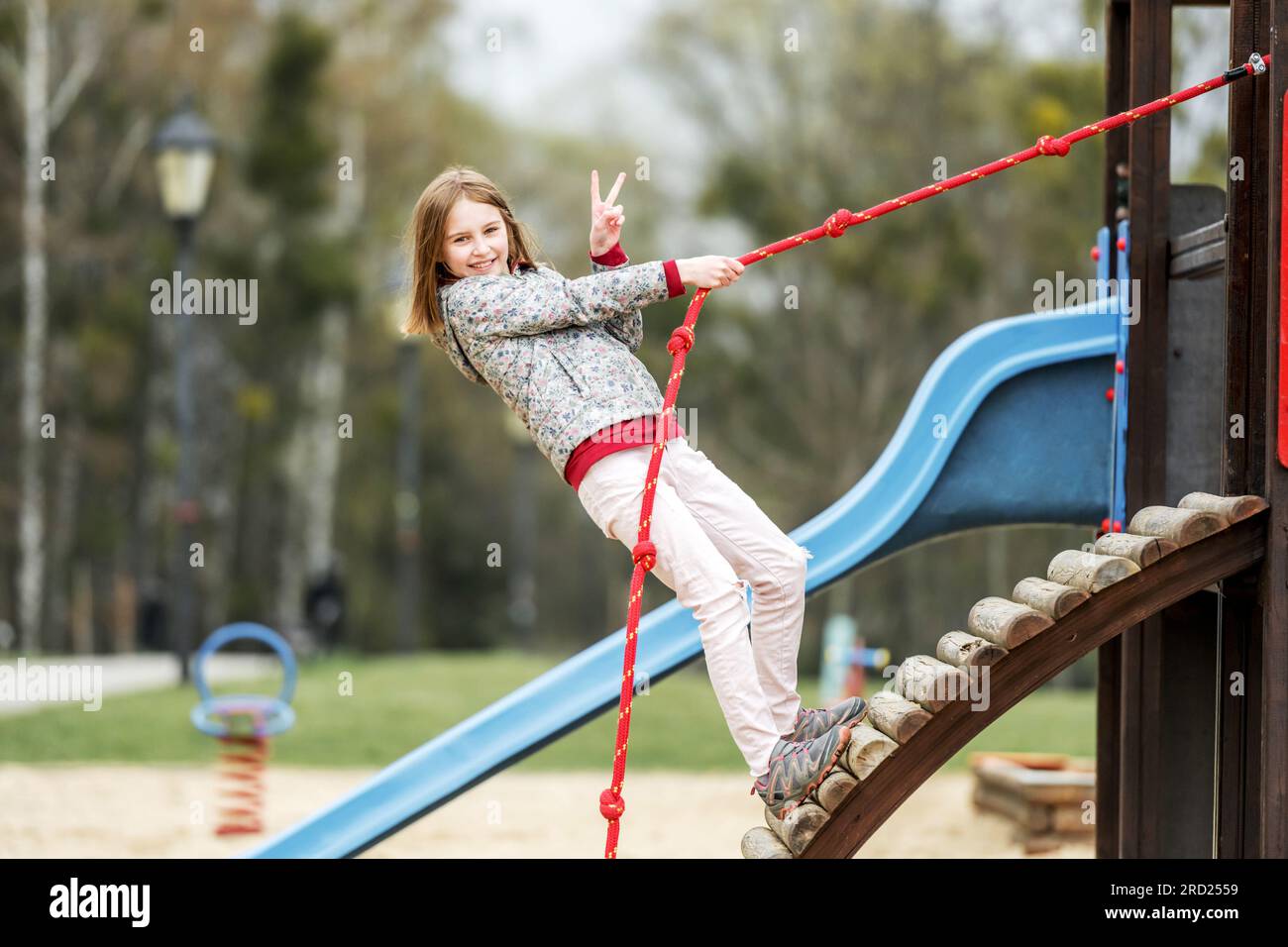 Funny little girl playing on the playground with rope Stock Photo - Alamy