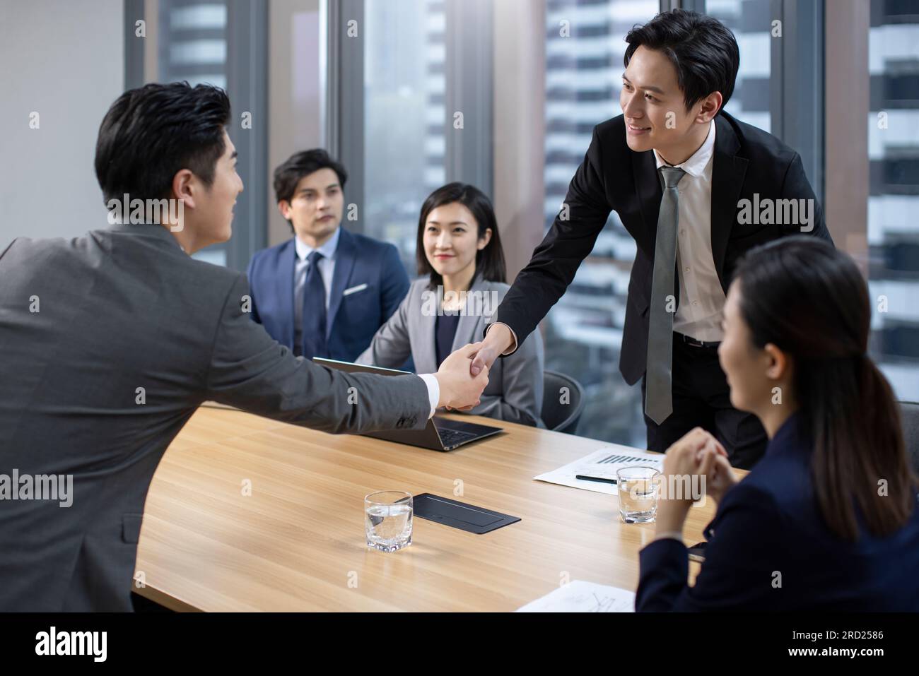 Successful Chinese business people shaking hands in meeting room Stock ...