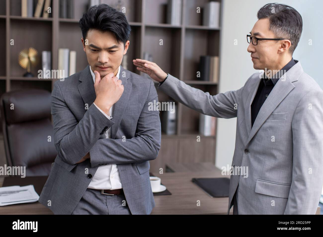 Chinese businessman consoling his colleague Stock Photo - Alamy