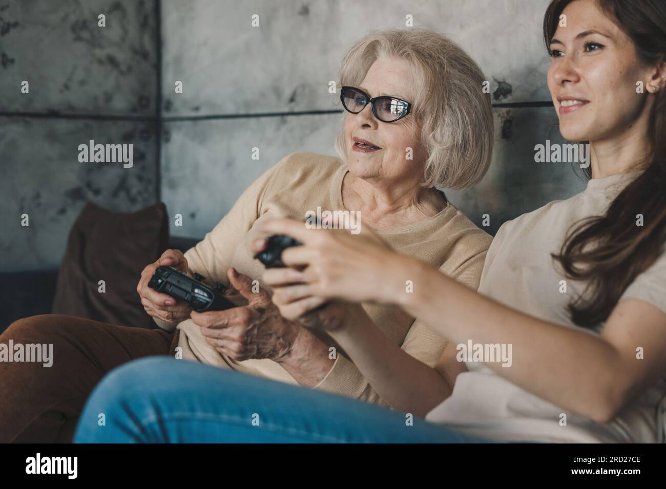 Excited senior gamer woman goung and her daughter sitting on a sofa and ...