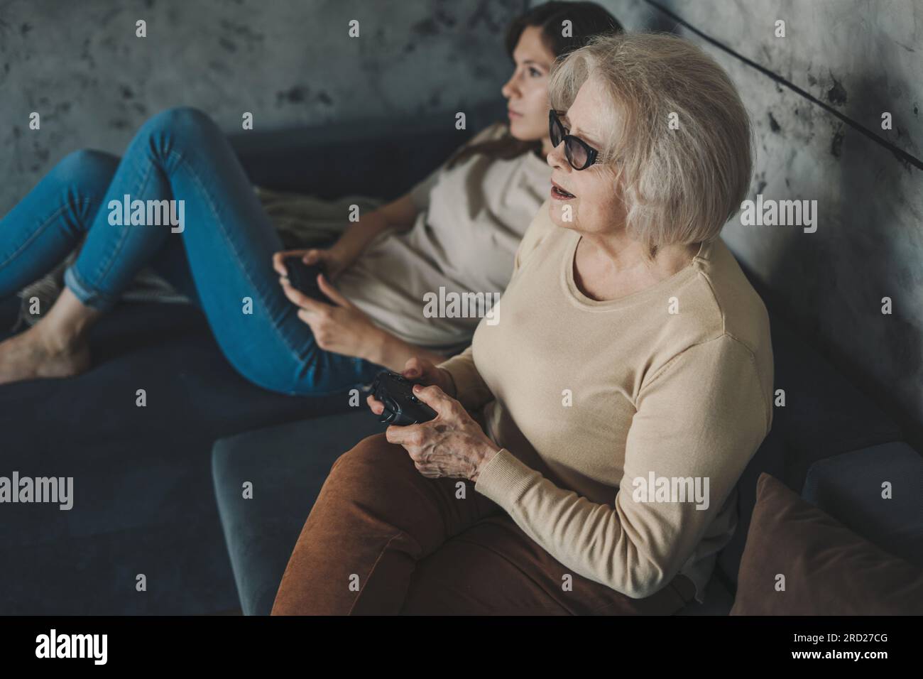 Woman with her grandmother playing video game using controller or ...