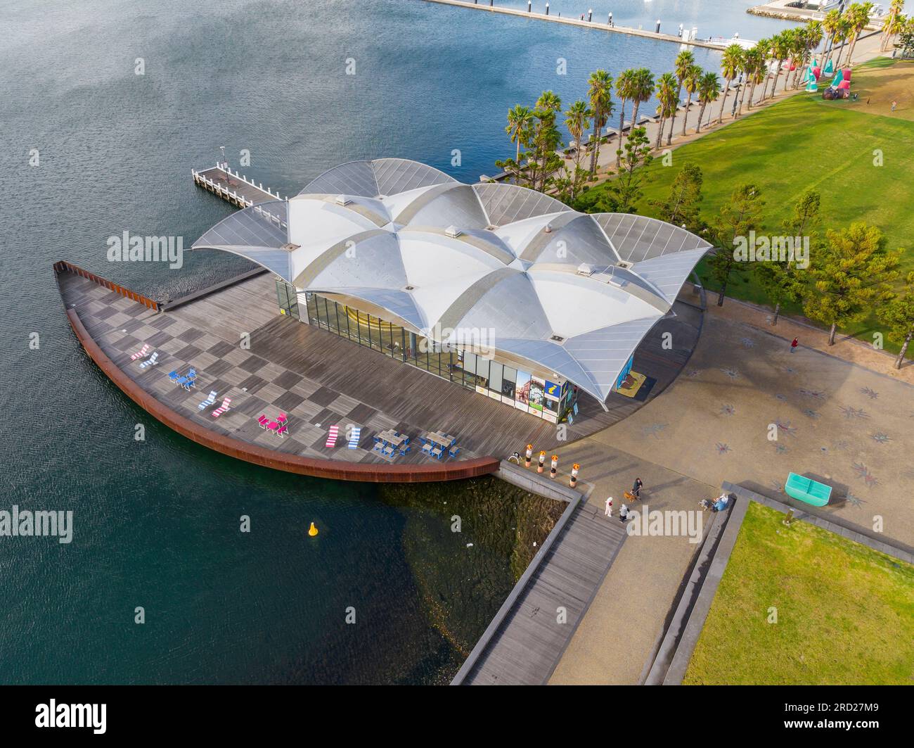 Aerial view of a modern waterfront pavilion, behind a curved pier at ...