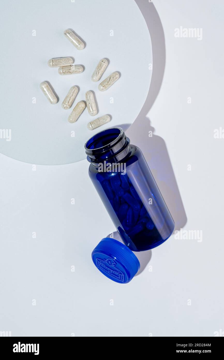 Open dietary supplement bottle with transparent capsules on white ...