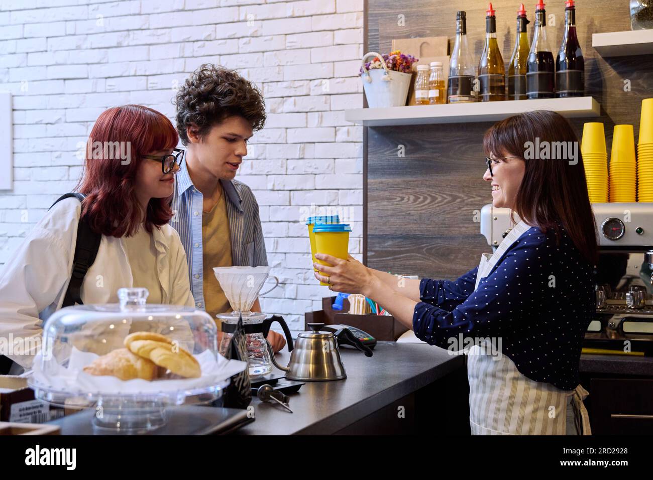 Female coffee shop worker serving customers giving paper cups of ...