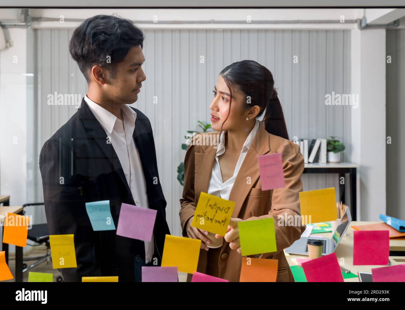 A professional man and woman stand together, engaged in a brainstorming ...