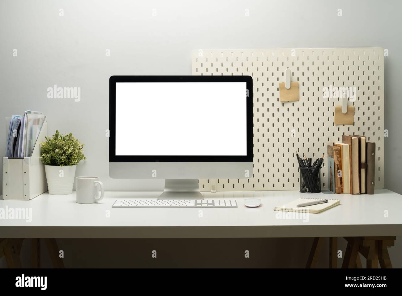 Blank empty desktop computer, potted plant and books on white table ...