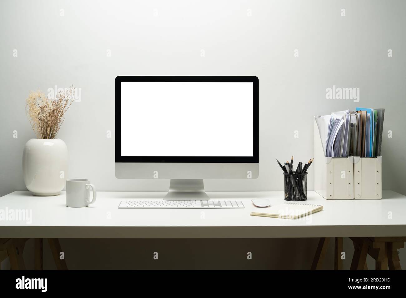 Blank empty desktop computer, potted plant and books on white table ...