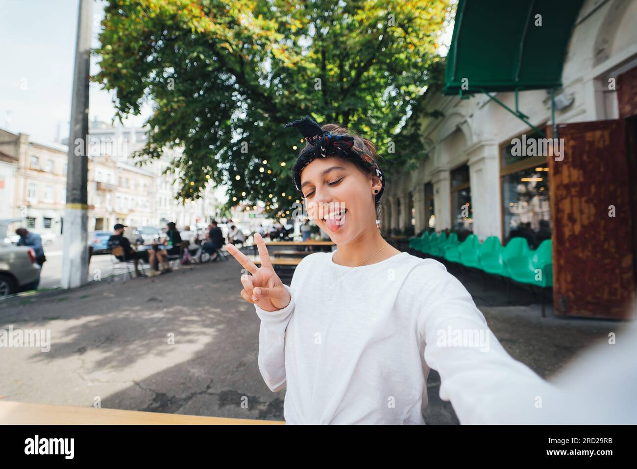 Girl shows v-sign smiling with closed eyes taking selfie on camera ...