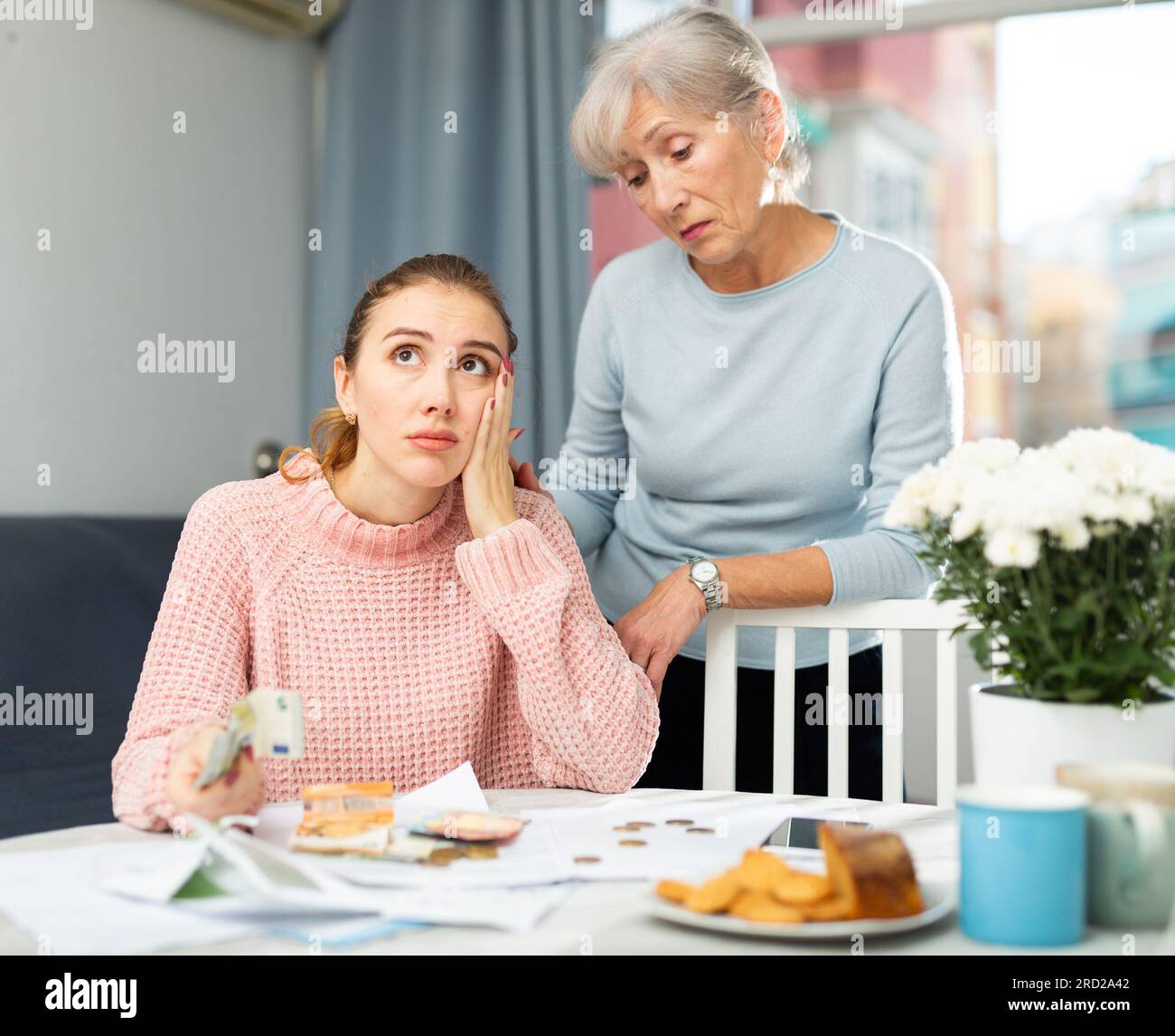 Upset young woman with elderly mother calculating running costs of ...