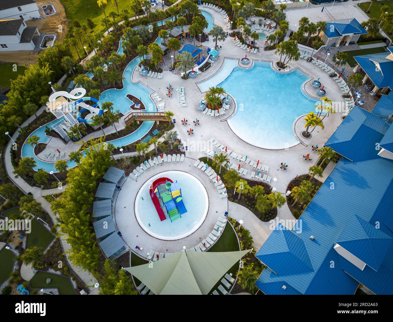 Looking down at a resorts club house pools with water rides and chairs ...