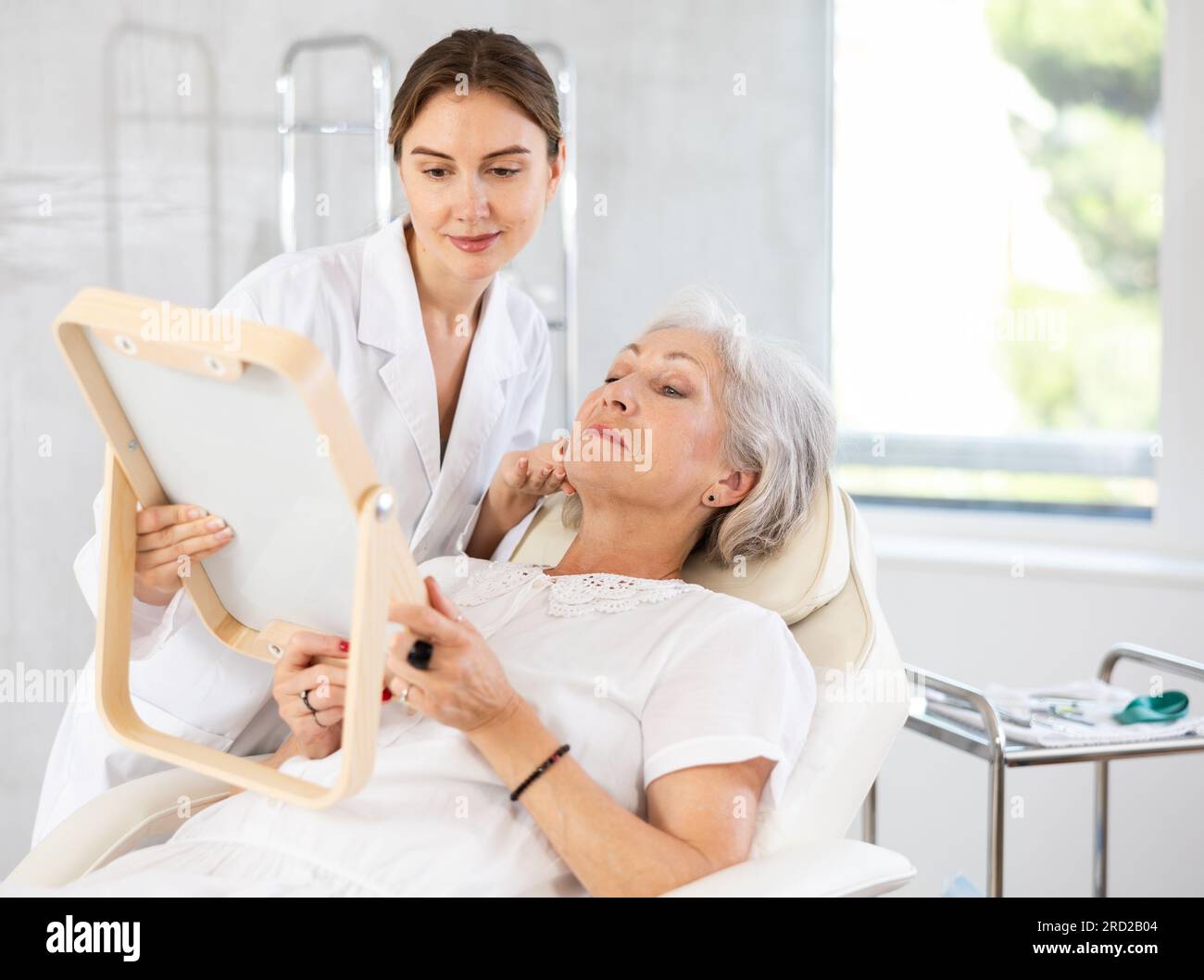 Elderly patient looking in mirror at clinic Stock Photo - Alamy