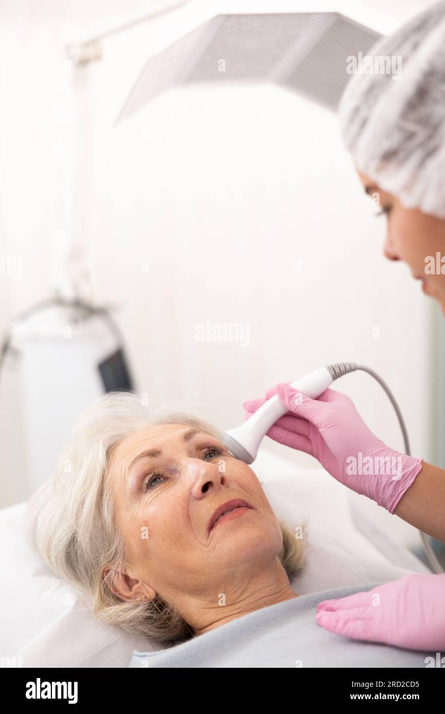 Old woman having face laser therapy procedure Stock Photo - Alamy