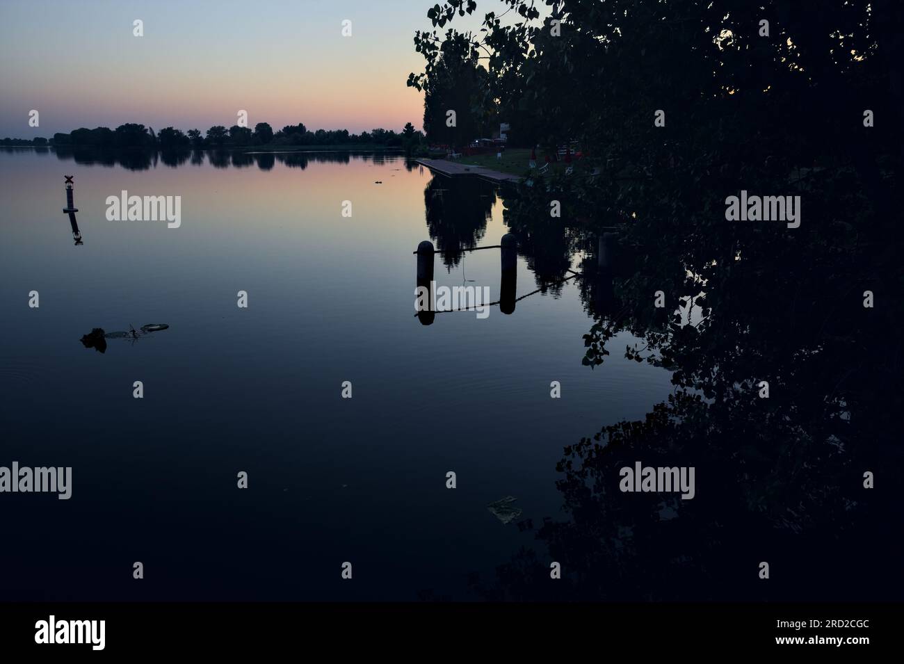 Riverside at sunset with its reflection casted in the water at sunset ...