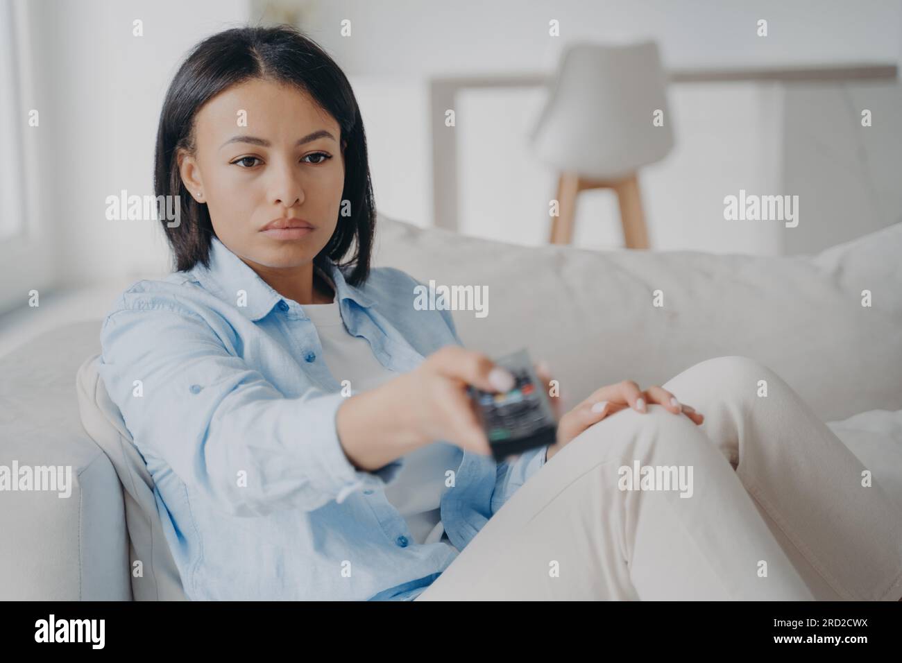 Bored young female holding tv remote control change channels lost in ...