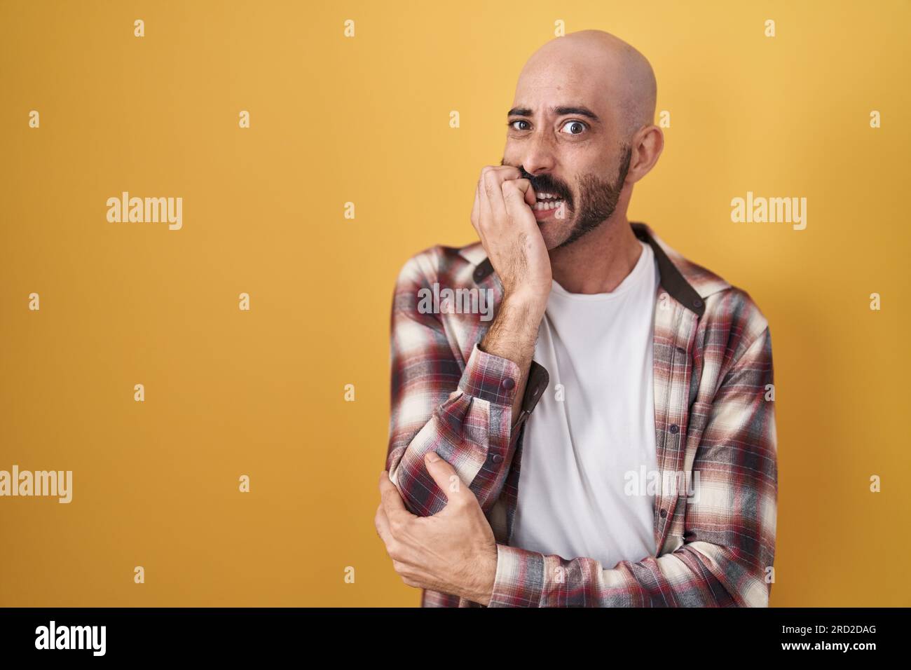 Hispanic man with beard standing over yellow background looking ...