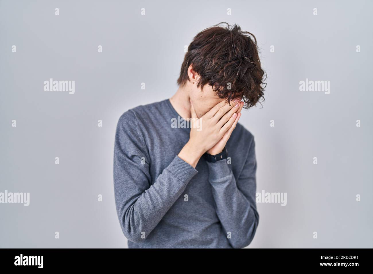 Young man standing over isolated background with sad expression ...