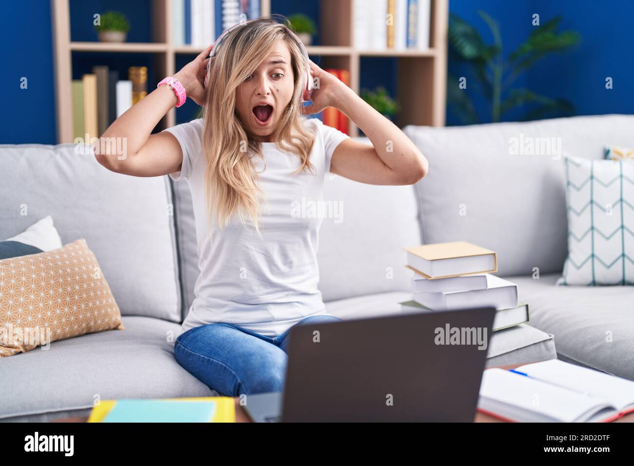 Young blonde woman studying using computer laptop at home crazy and ...