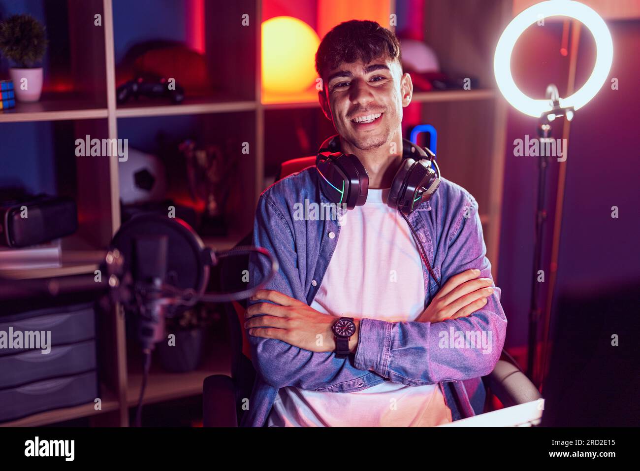 Young hispanic man streamer smiling confident sitting with arms crossed ...