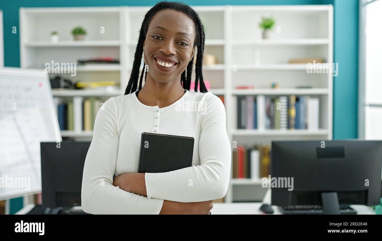 African american woman student holding book standing at university ...