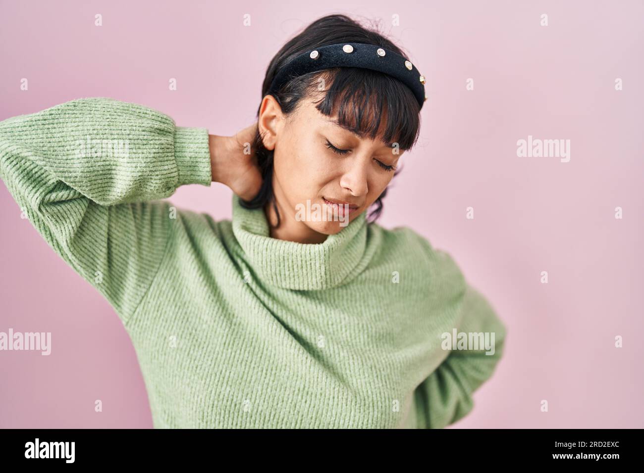 Young beautiful woman standing over pink background suffering of neck ...