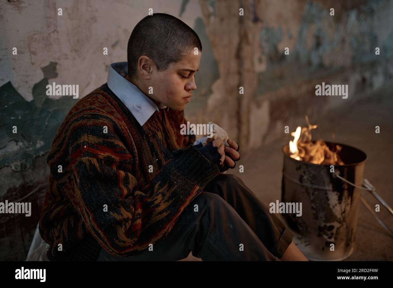 Poor homeless woman eating sandwich while warming at bonfire Stock ...