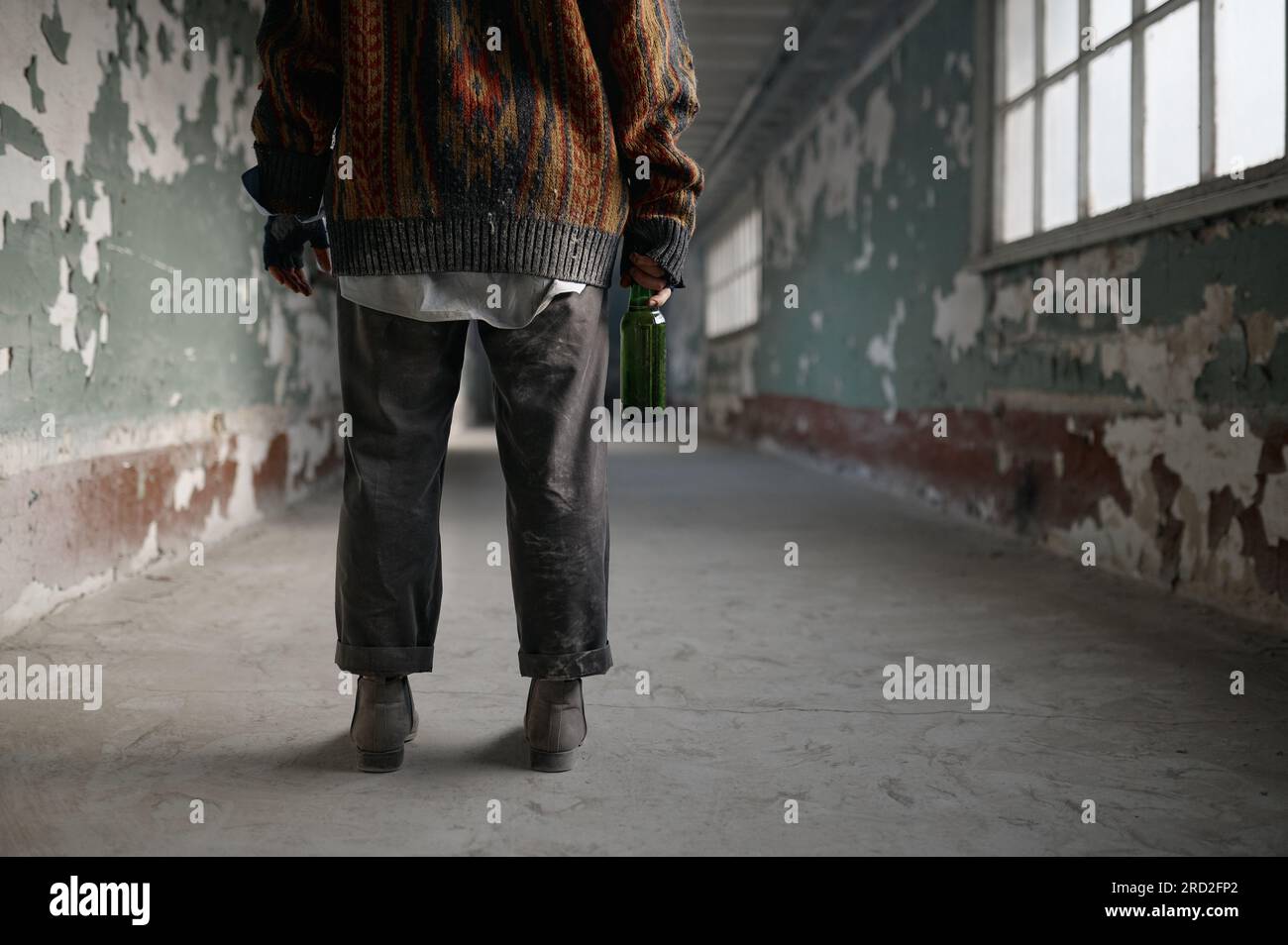 Back view of homeless woman beggar with bottle of alcohol drink in hand ...