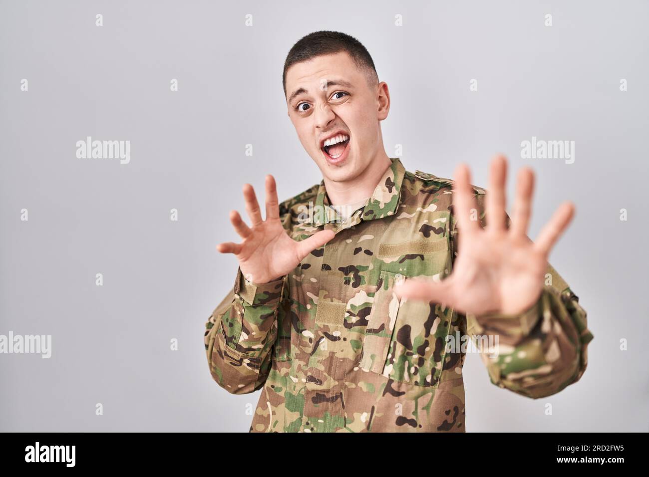 Young man wearing camouflage army uniform afraid and terrified with ...