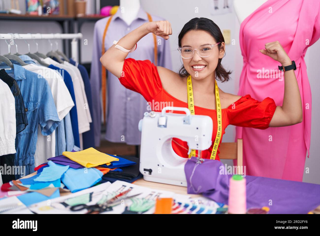 Hispanic young woman dressmaker designer using sewing machine showing ...