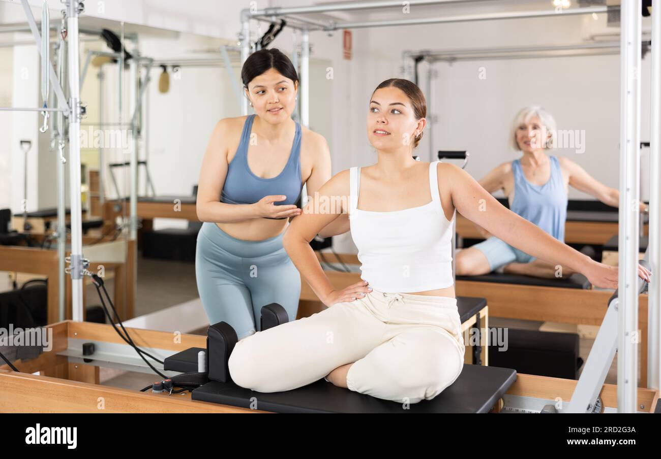 Woman doing pilates in fitness studio with female personal trainer ...