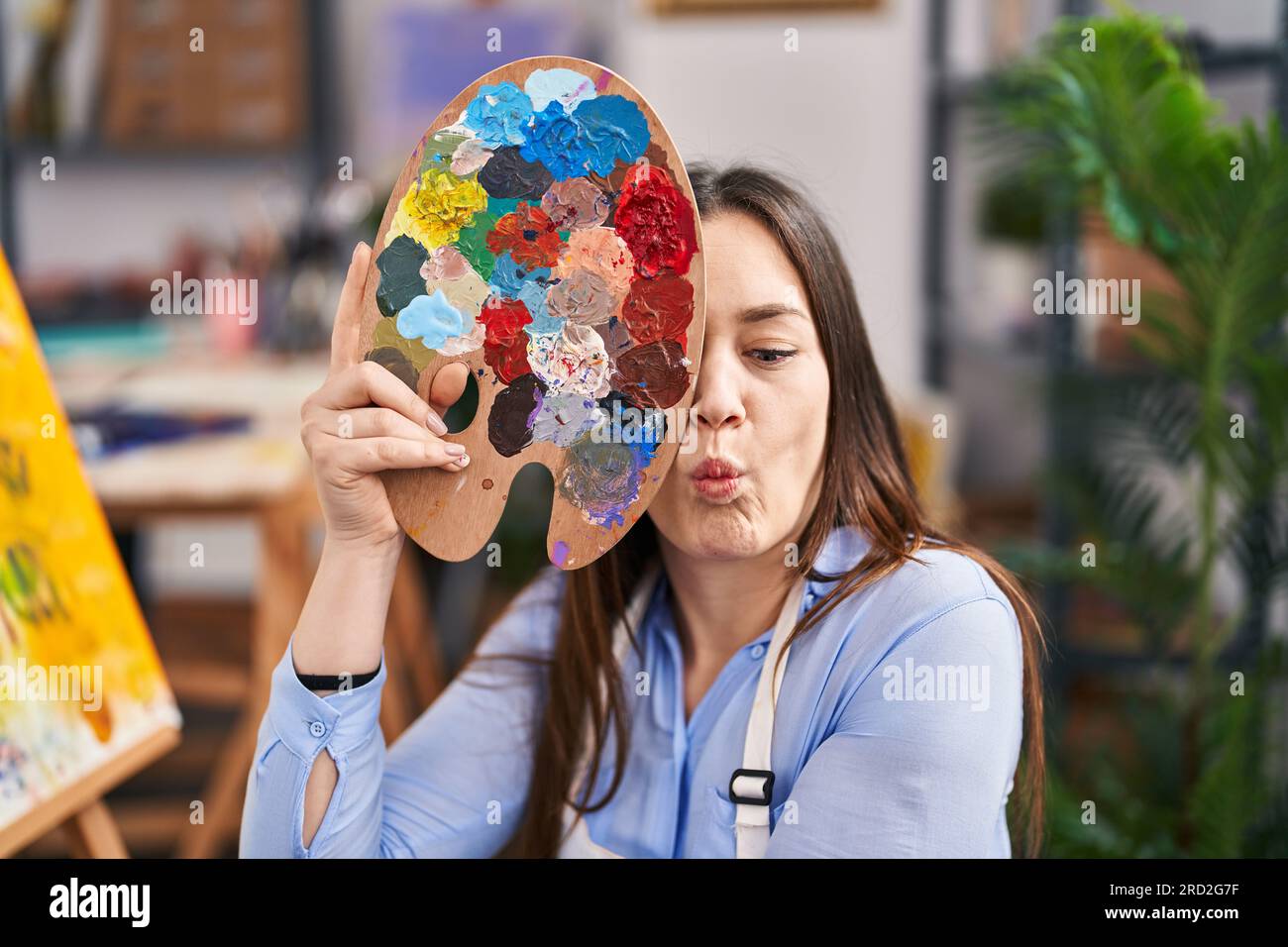 Young brunette woman covering face with painter palette making fish ...