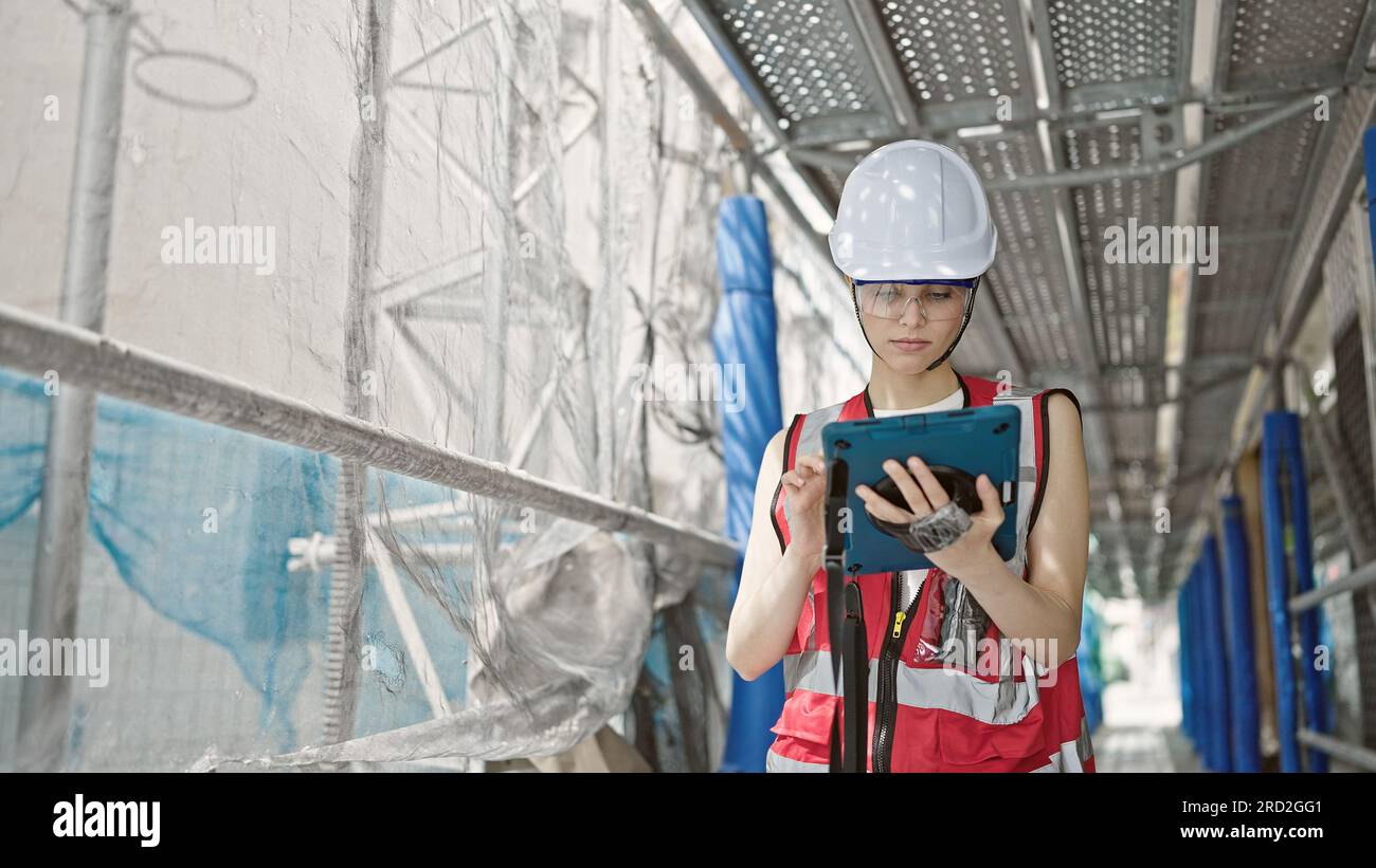 Young beautiful hispanic woman builder using touchpad at street Stock ...