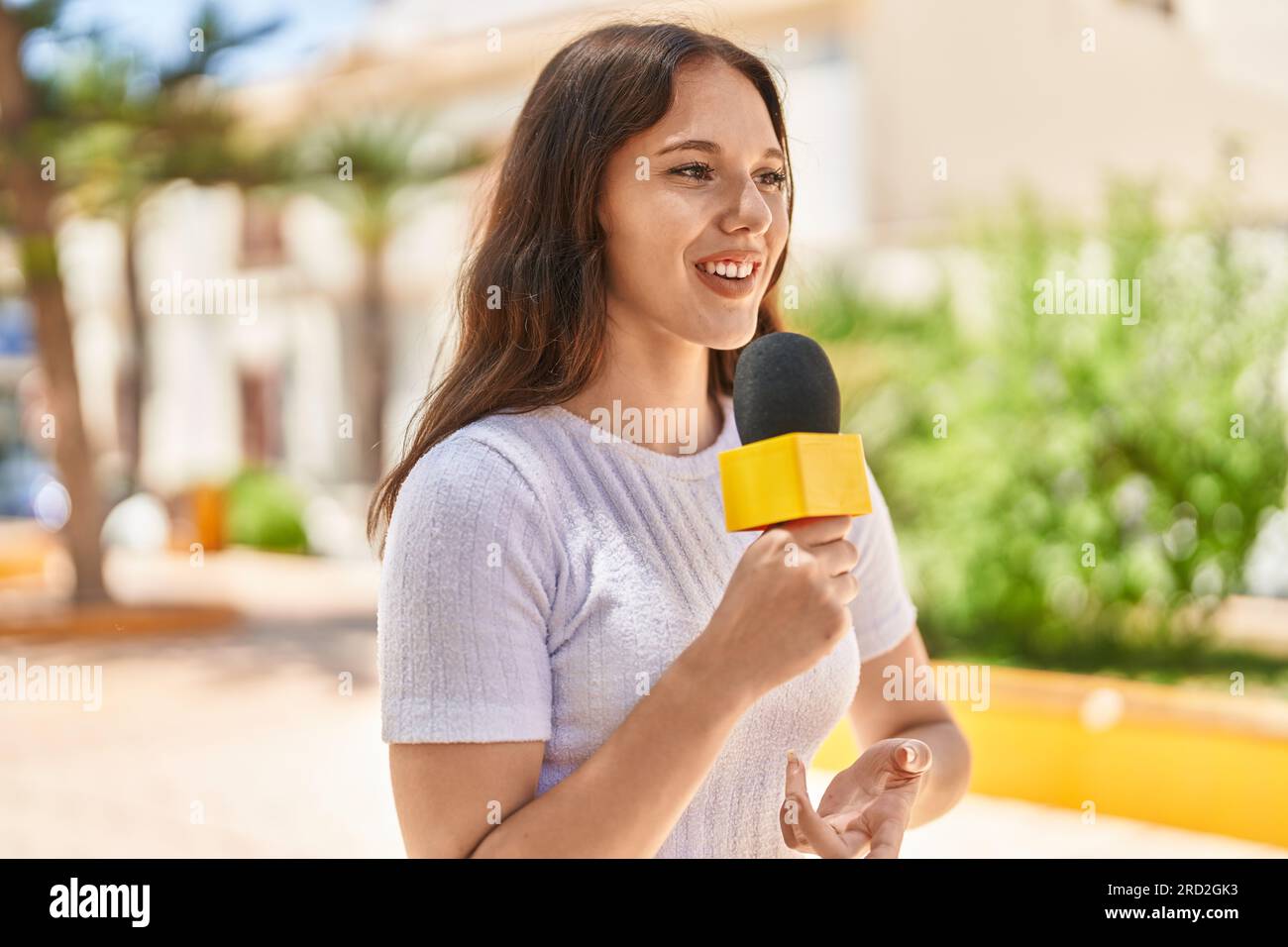 Young woman reporter working using microphone at park Stock Photo - Alamy
