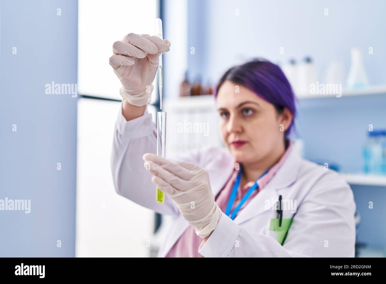 Young beautiful plus size woman scientist pouring liquid on test tube ...