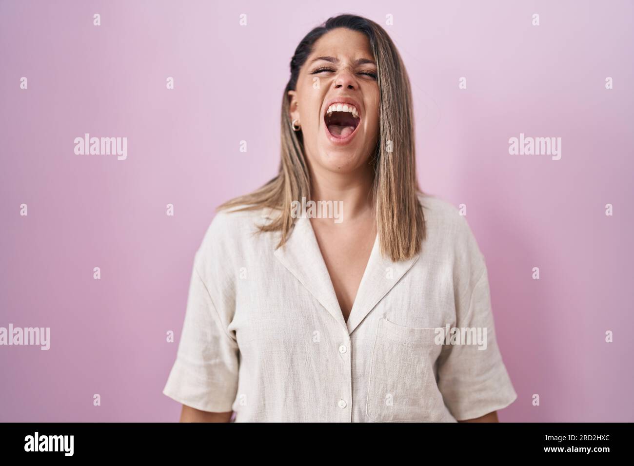 Blonde woman standing over pink background angry and mad screaming ...