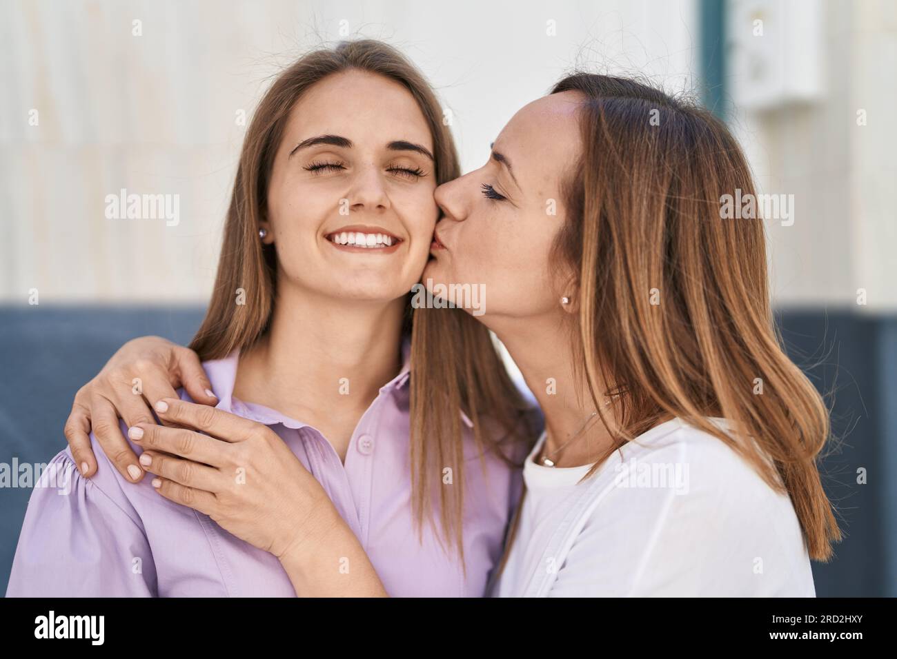 Two women mother and daughter hugging each other and kissing at street Stock Photo - Alamy