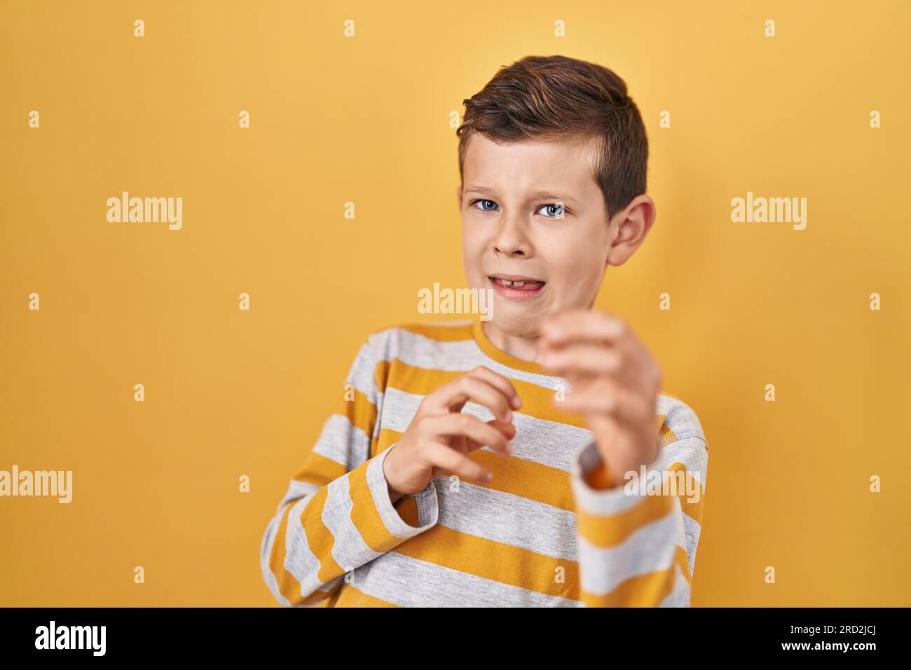 Young caucasian kid standing over yellow background disgusted ...