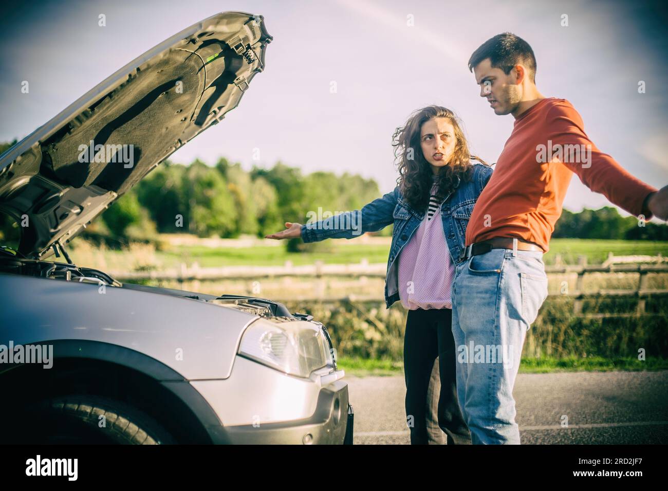A young couple had a car breakdown on the road. They stand very upset ...