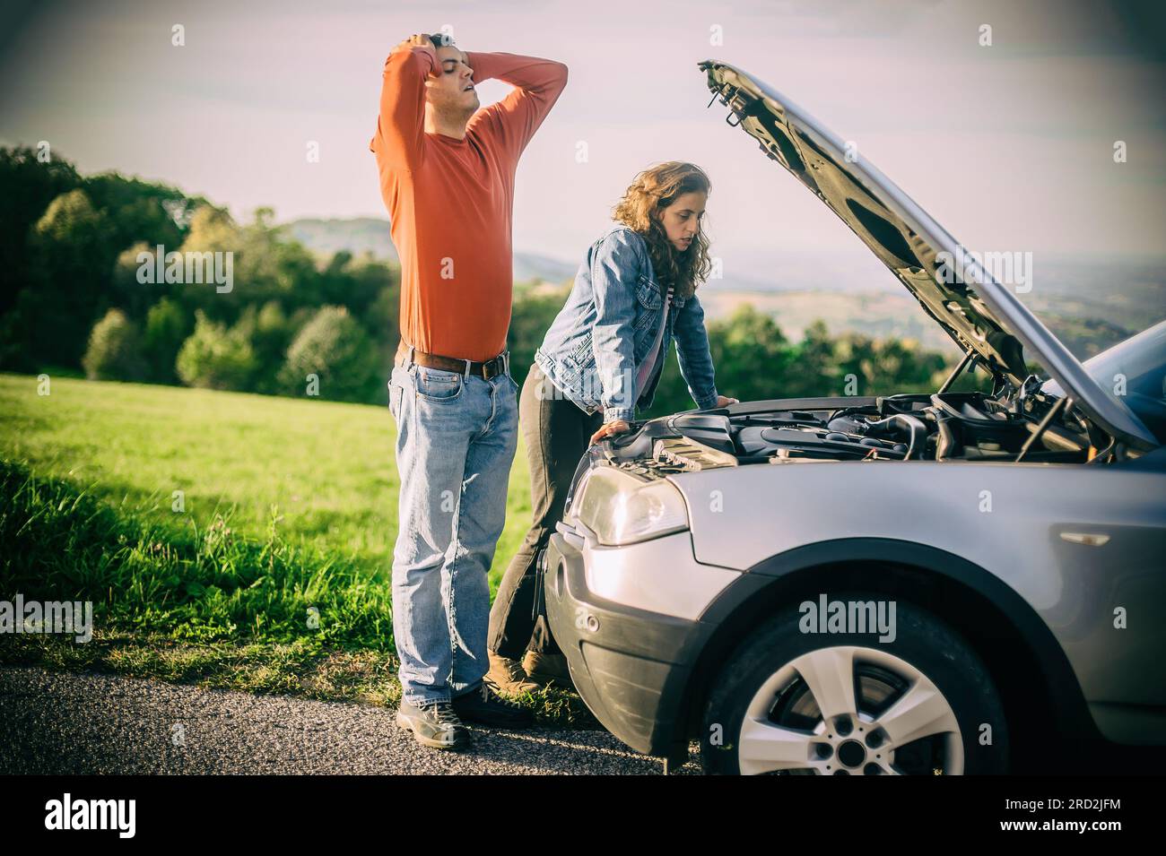 A young couple had a car breakdown on the road. They stand very upset ...