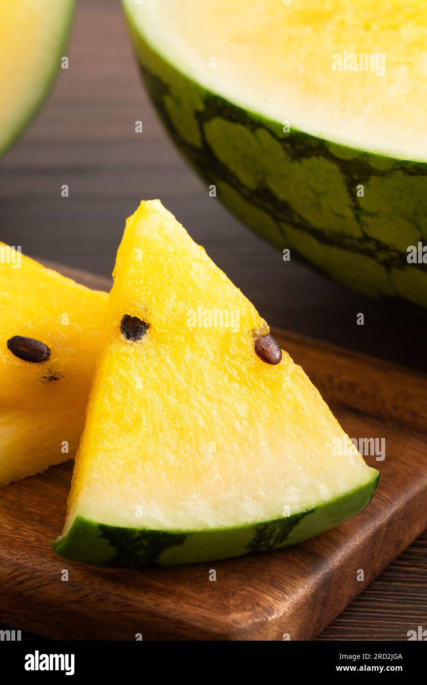 Sliced yellow golden watermelon in a plate on wooden table background ...