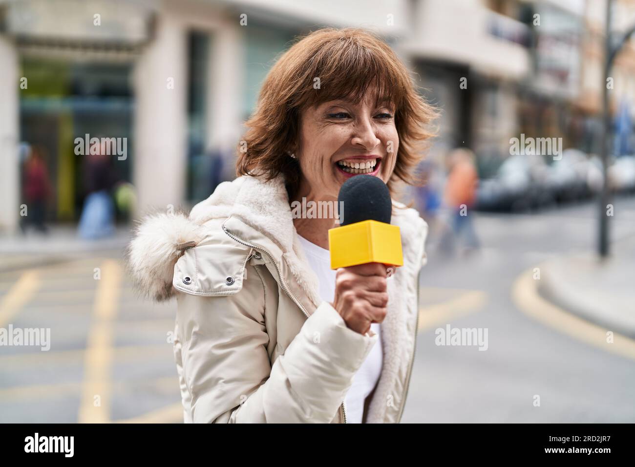 Middle age woman reporter working using microphone at street Stock ...