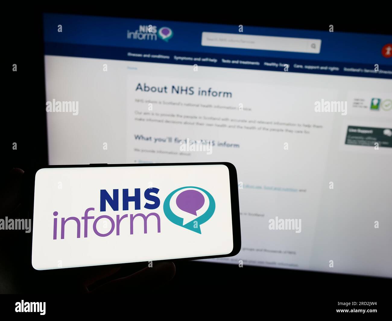 Person holding smartphone with logo of Scottish health information service NHS inform on screen ...