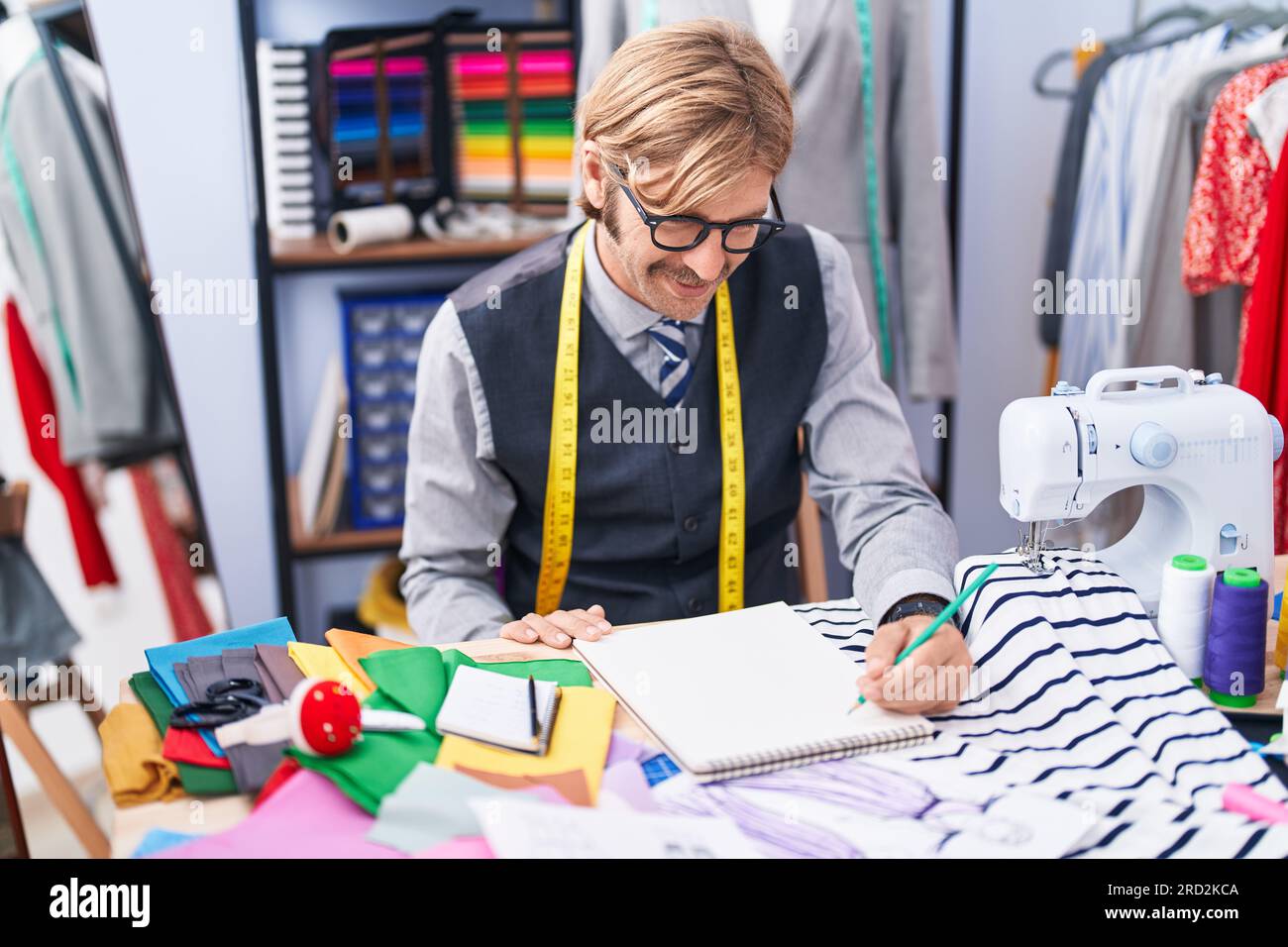 Young blond man tailor smiling confident drawing on notebook at ...