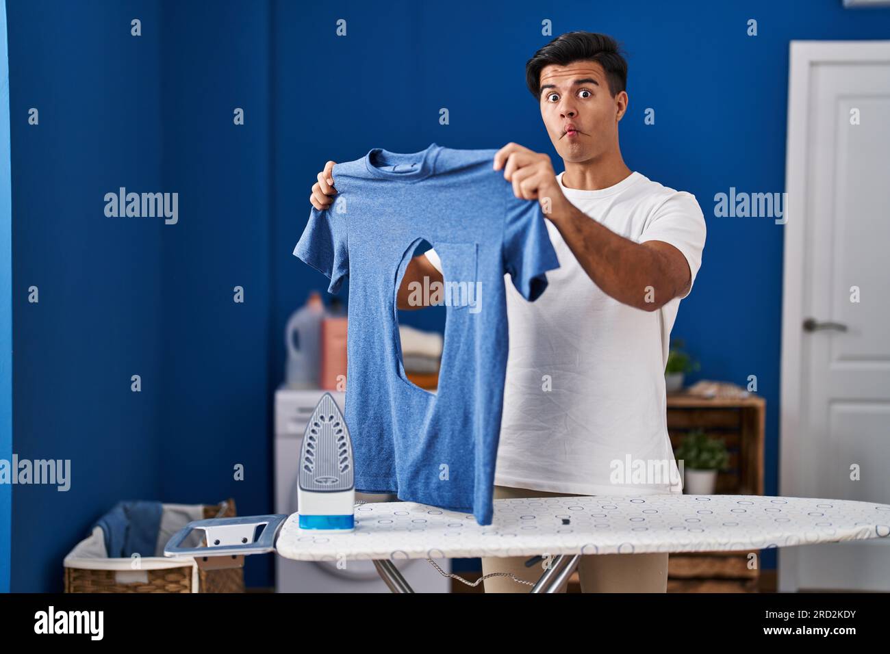 Hispanic man ironing holding burned iron shirt at laundry room making ...