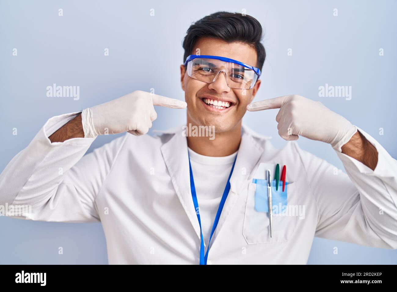 Hispanic man working as scientist smiling cheerful showing and pointing ...