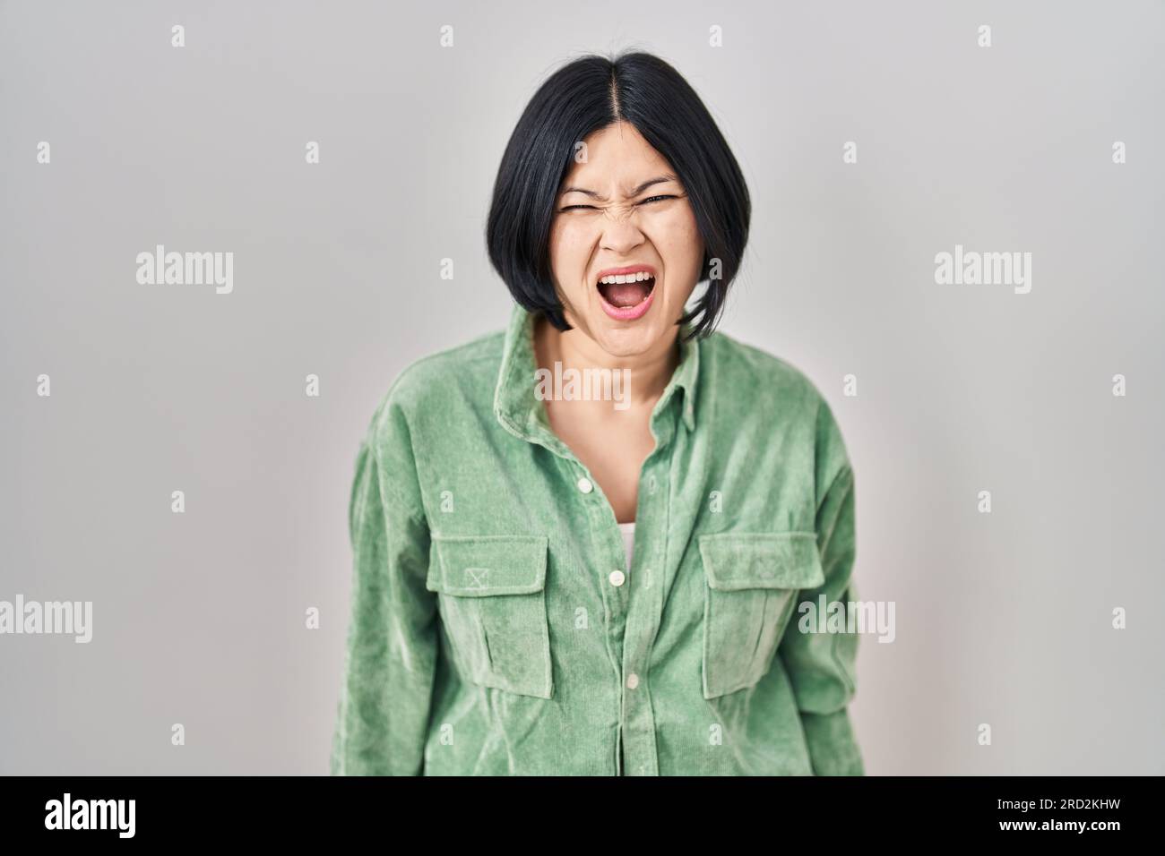 Young asian woman standing over white background angry and mad ...