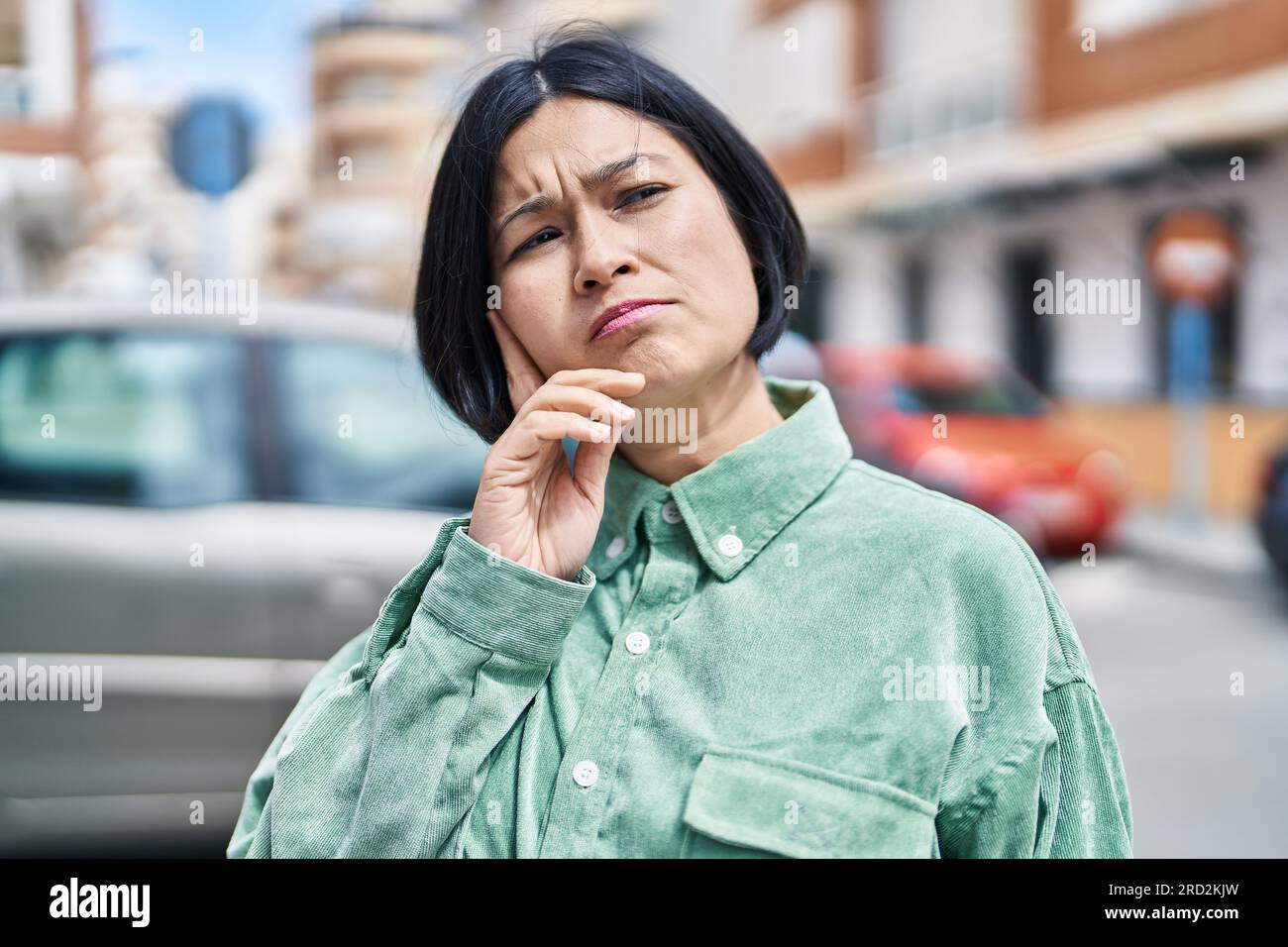 Young chinese woman standing with doubt expression at street Stock ...