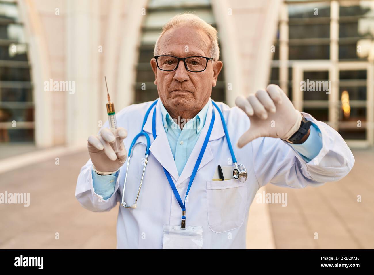 Senior doctor with grey hair holding syringe with angry face, negative ...