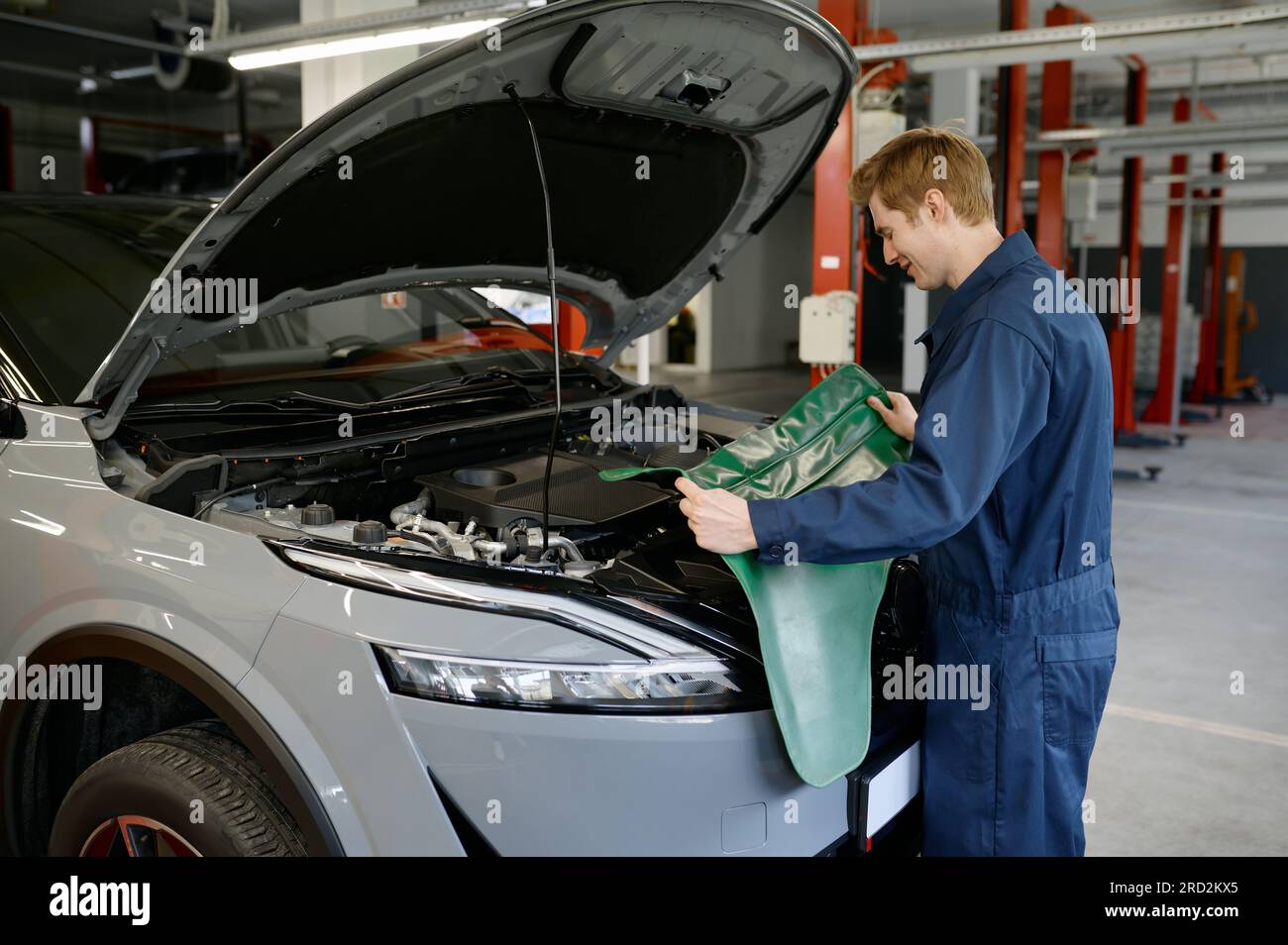 Male mechanic using protective cape for work in engine repair service ...